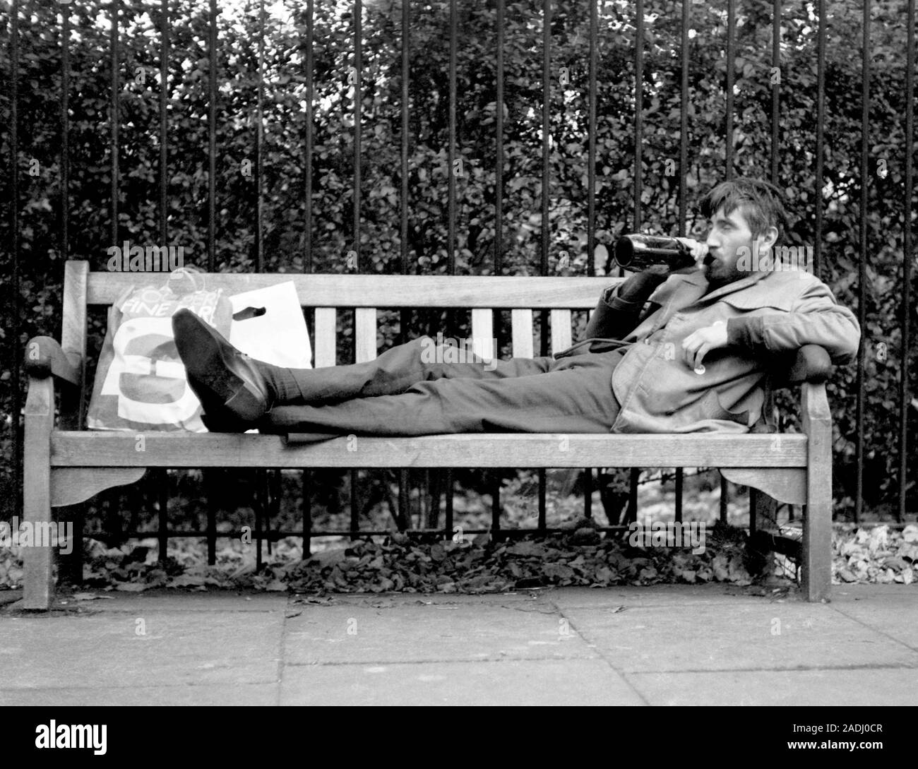 MODEL RELEASED. Alcoholism. Drunk man lying on a bench Stock Photo - Alamy