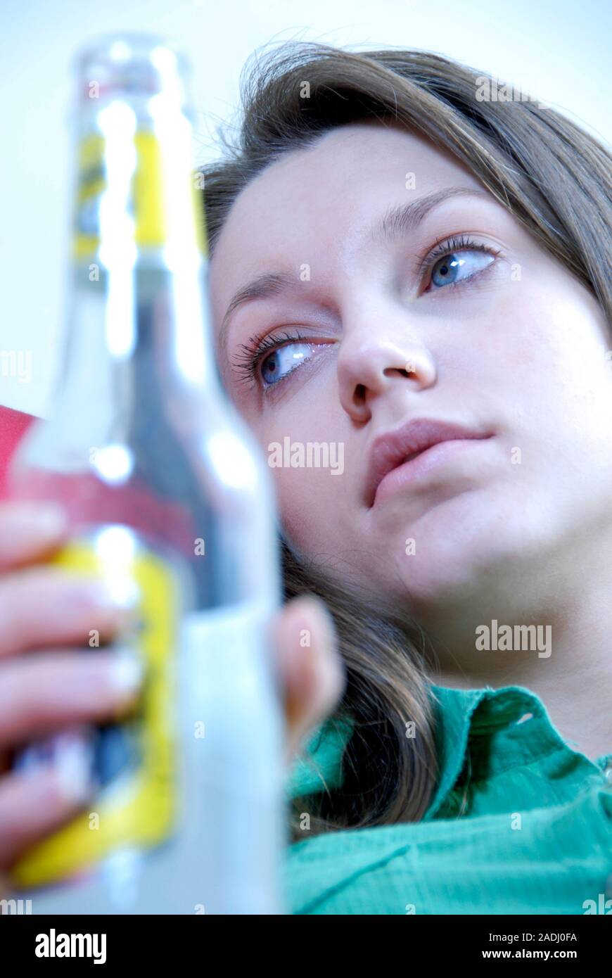 MODEL RELEASED. Problem drinking. Young woman holding a bottle of ...