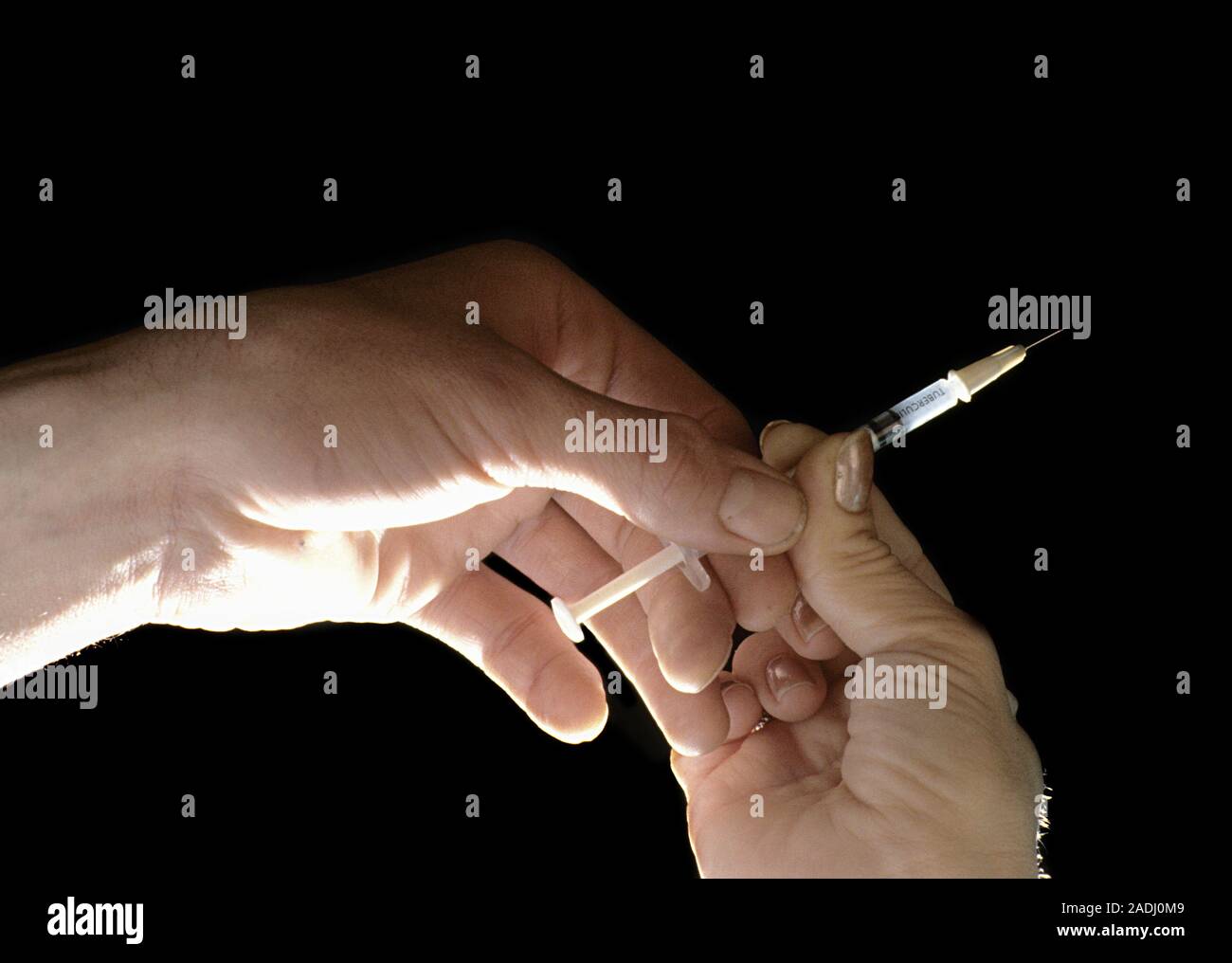 Drug abuse. Close-up view of two hands sharing a hypodermic syringe ...