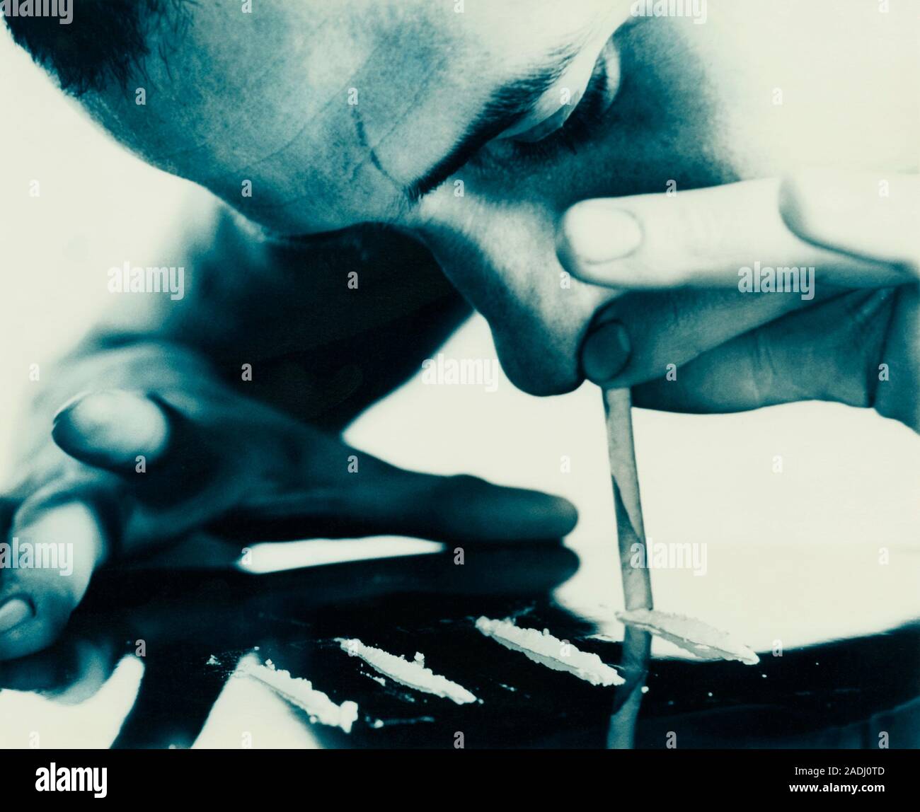 Cocaine snorting. Man snorting a line of cocaine through a rolled-up ...