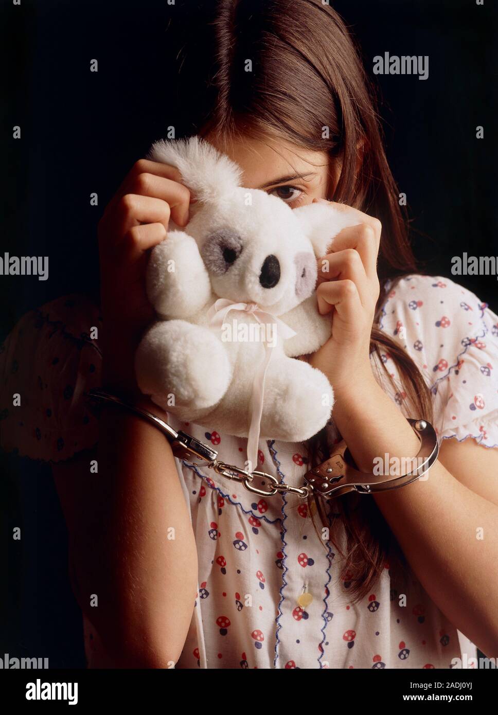Child Abuse. Distressed and handcuffed victim of child abuse hides her ...