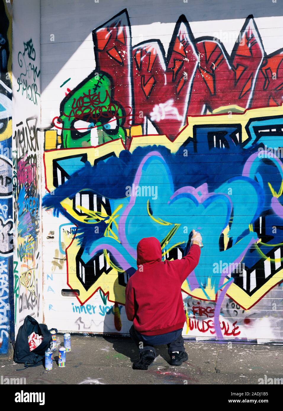 Graffiti artist. Youth using an aerosol spray paint can to paint a ...