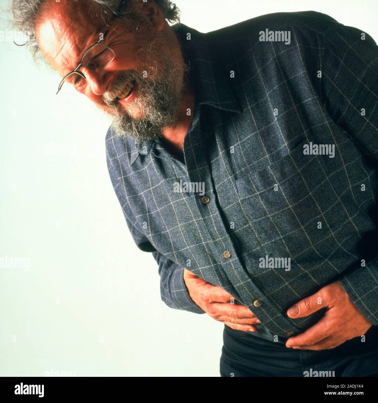 Stomach pain. 57 year old man clutching his stomach in pain. Pain or ...