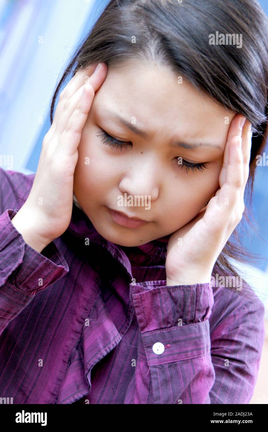 MODEL RELEASED. Headache. Woman with a headache holding her painful ...