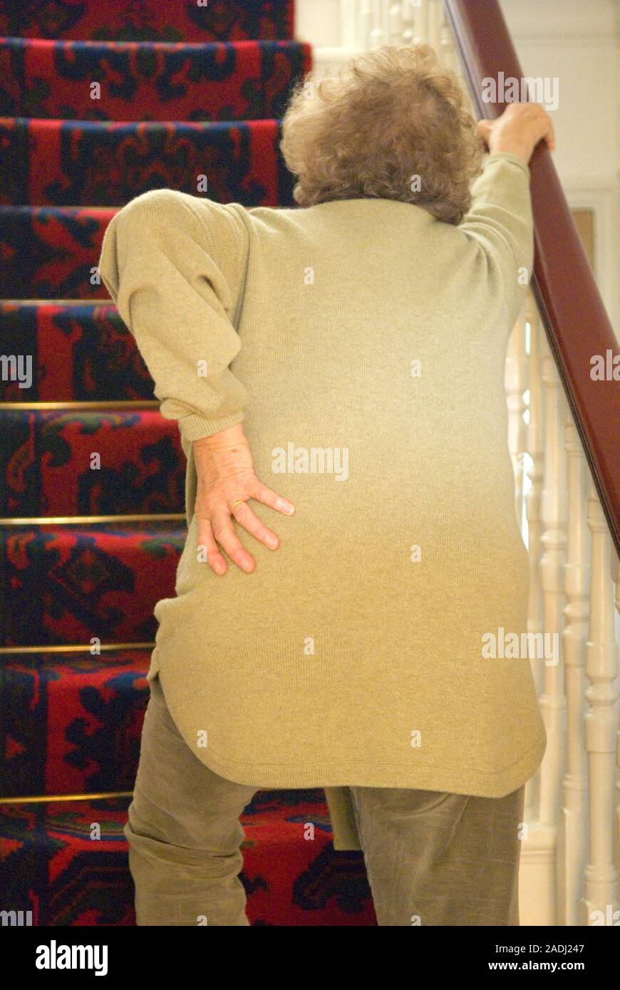 MODEL RELEASED. Back pain. Elderly woman with a sore back climbing a ...
