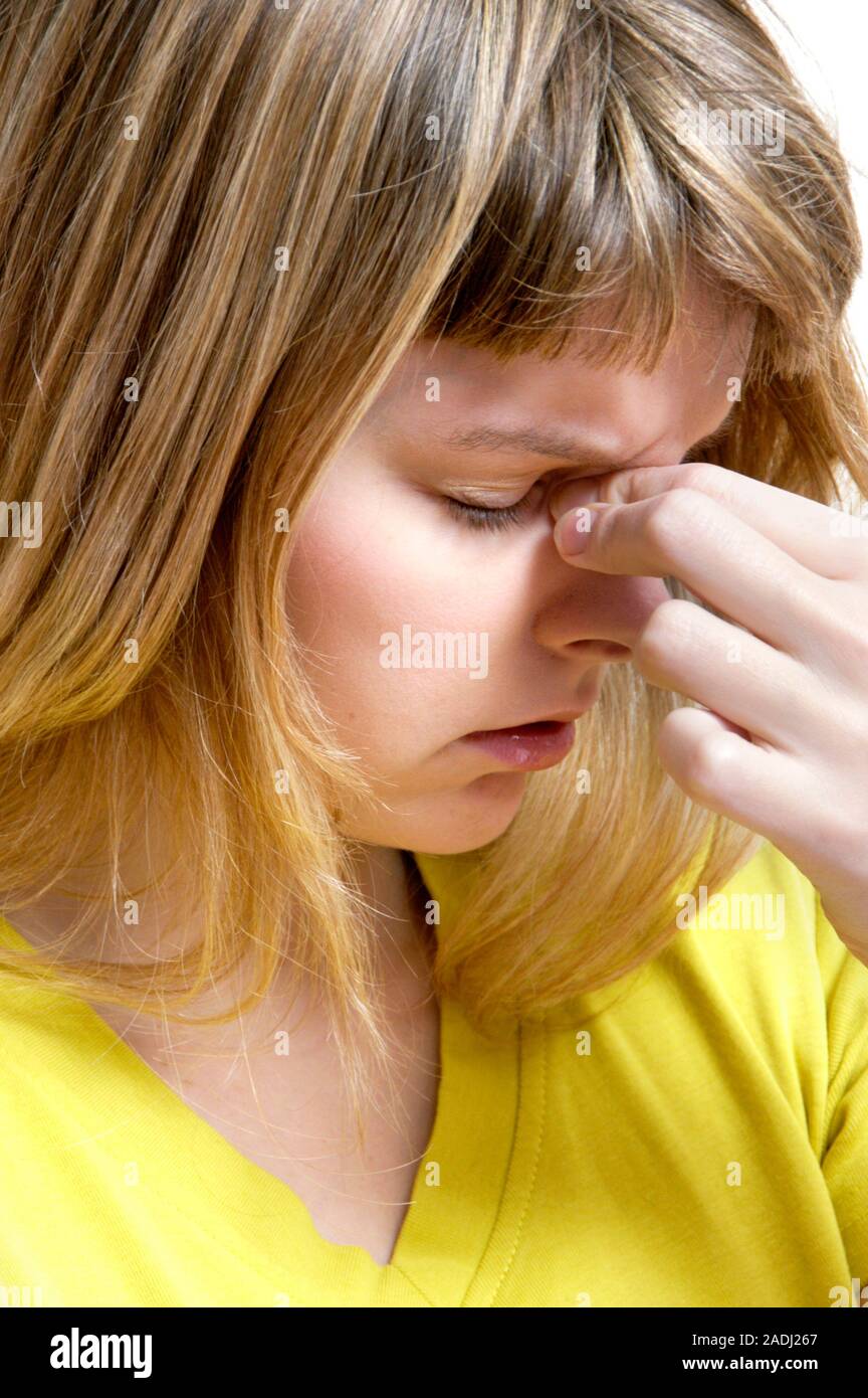 MODEL RELEASED. Sinus pain. 18-year-old woman squeezing the bridge of ...