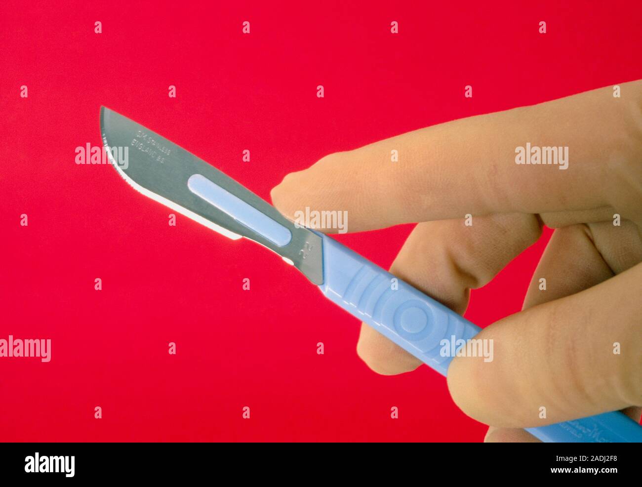 Scalpel. Gloved hand holding a disposable scalpel, a surgical knife ...