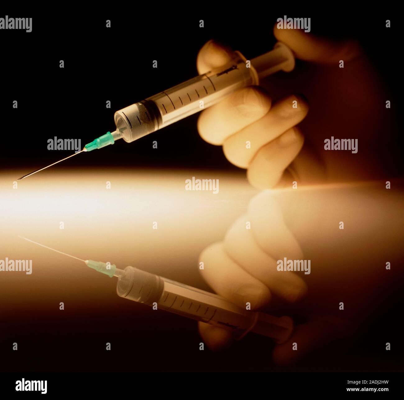 Syringe. Gloved hand holding a hypodermic syringe, with a reflection ...