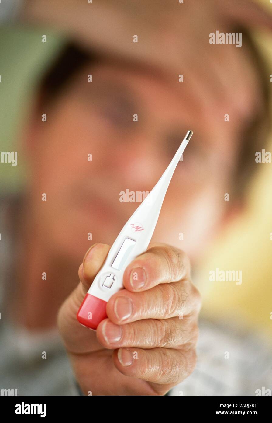 Digital thermometer. Man holding a digital thermometer while feeling ...