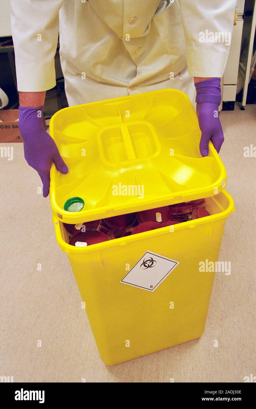 Clinical waste. Gloved hospital worker sealing a bin full of clinical ...