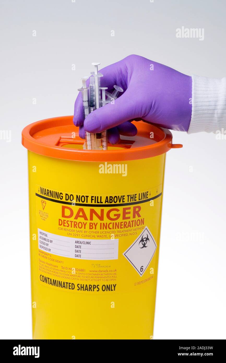 Disposal of contaminated sharps. Used syringes are being put in a ...