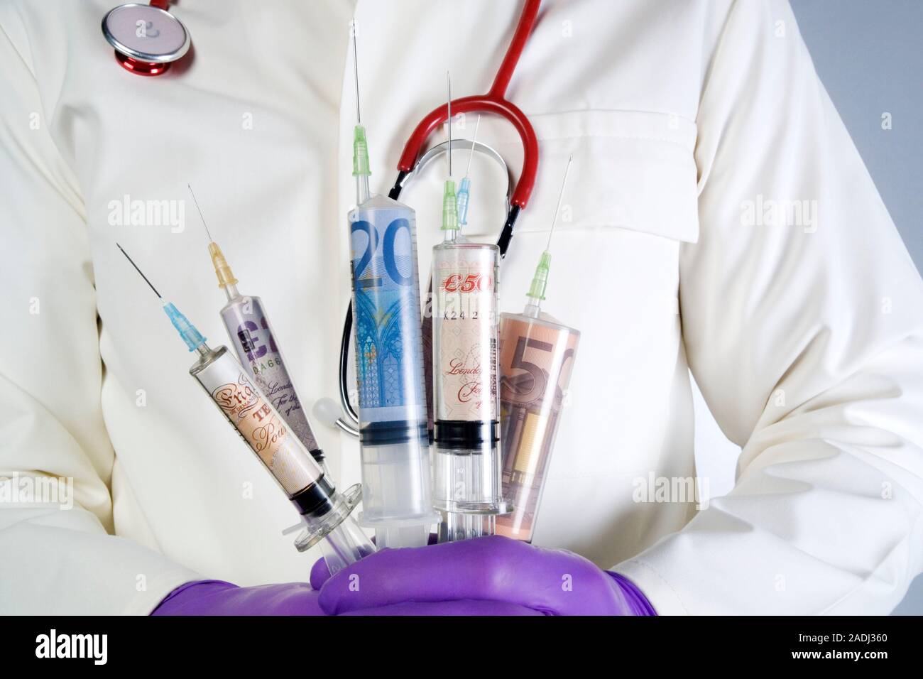Medical money. Conceptual image with a doctor holding syringes filled ...