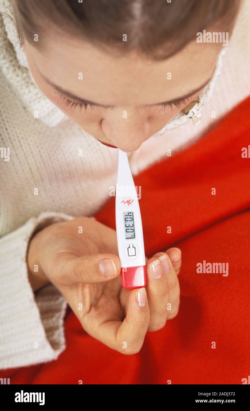 MODEL RELEASED. Thermometer. Woman using a digital thermometer to ...