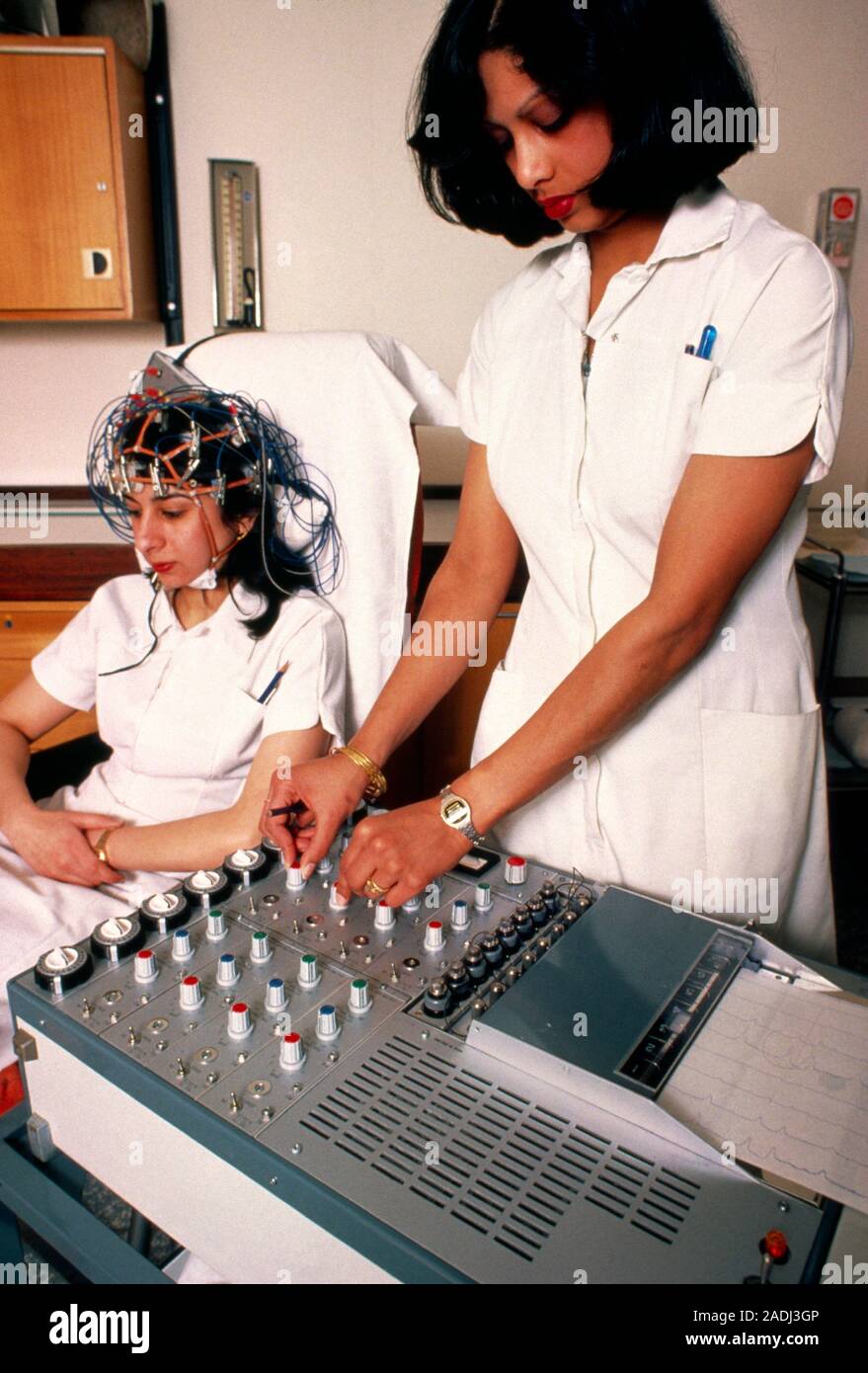 Young woman (background) undergoing an electroencephalogram (EEG ...