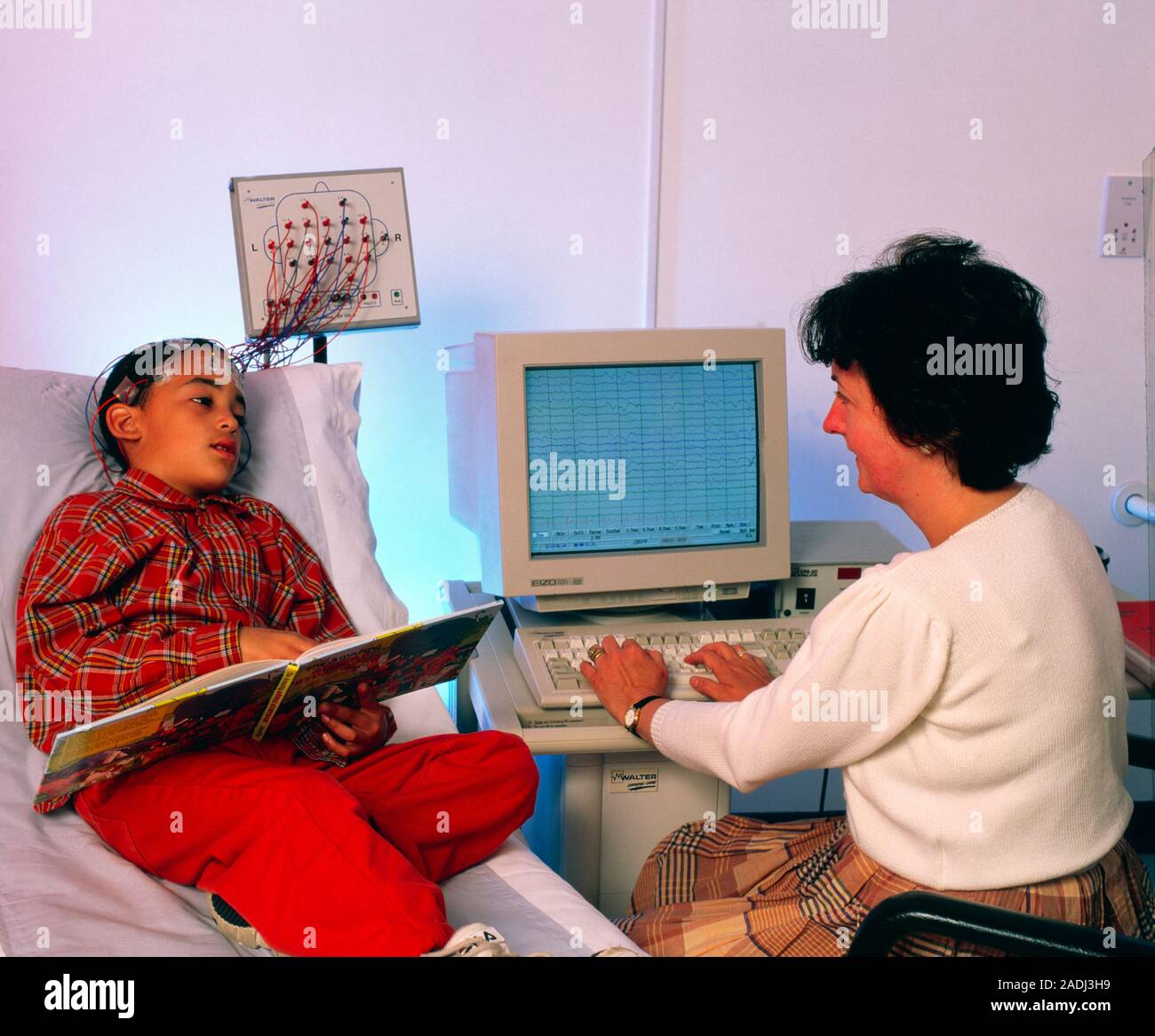 Electroencephalography. Doctor monitoring a young boy's brain activity ...