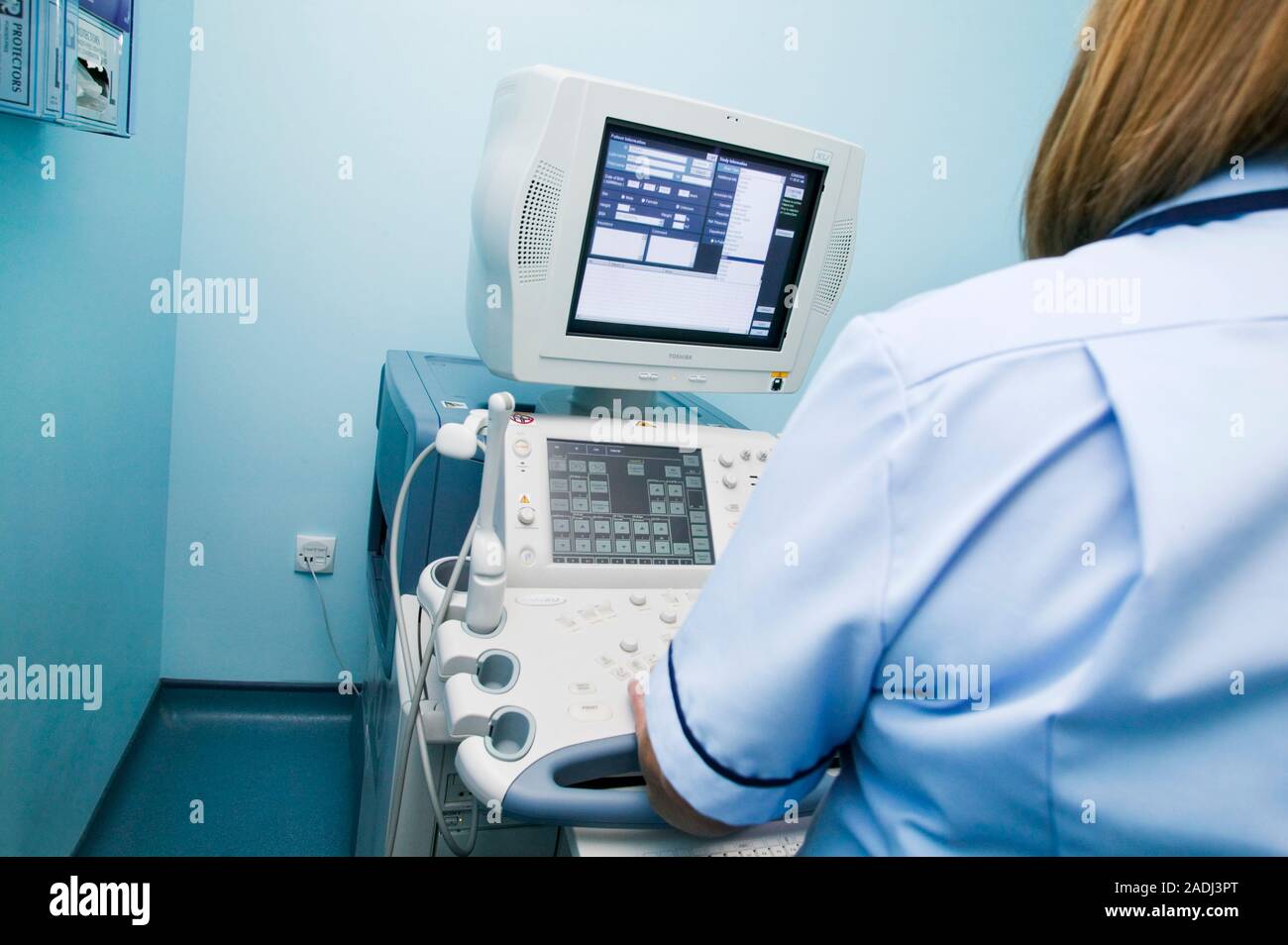 Ultrasound machine. Nurse preparing an ultrasound machine for use. An ...