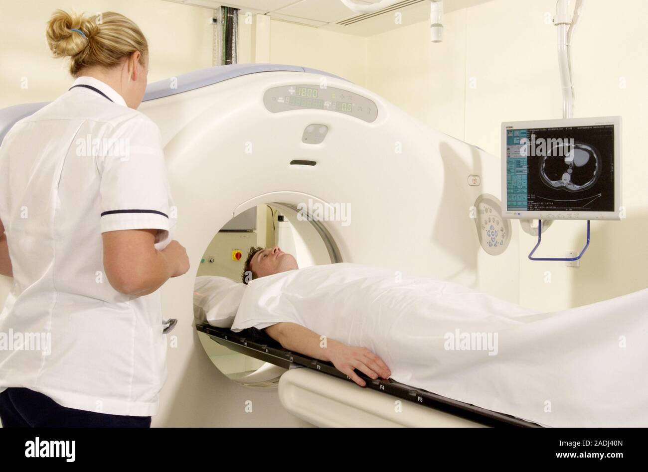 MODEL RELEASED. CT scanning. Radiographer watching a patient undergoing ...