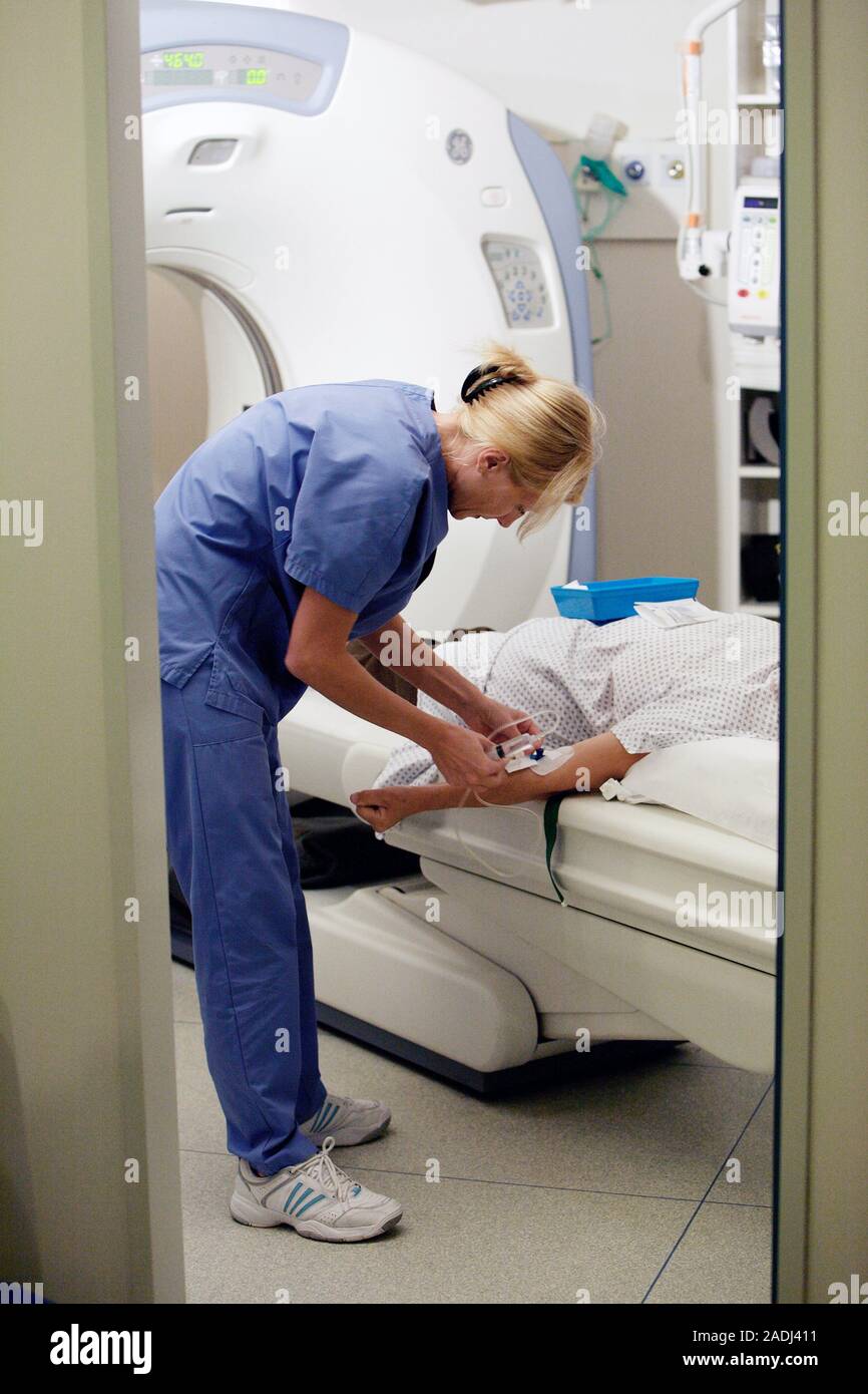 CT scanning. Radiographer administering intravenous fluid while ...