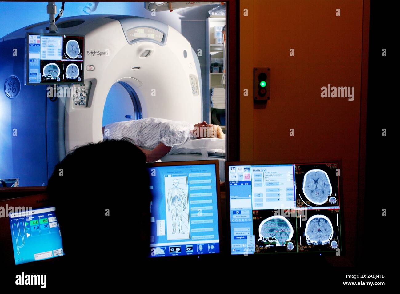CT scanning. Radiographer (silhouetted, lower left) analysing CT scan ...