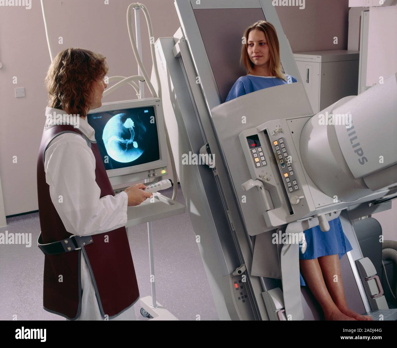 Barium meal X-ray. Radiographer conducts a barium meal stomach X-ray on ...