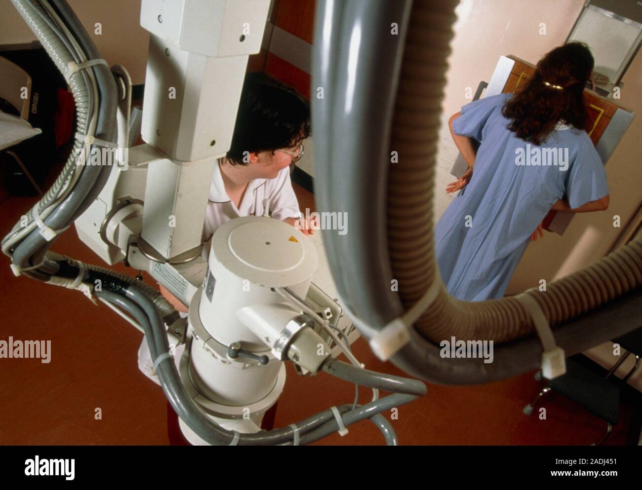 Chest X-ray. View of a female patient undergoing a chest X-ray. She is ...