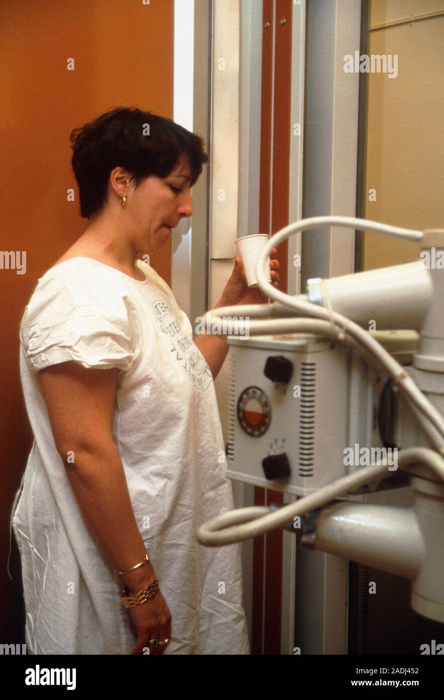 Barium swallow X-ray. Female patient swallowing barium during an X-ray ...