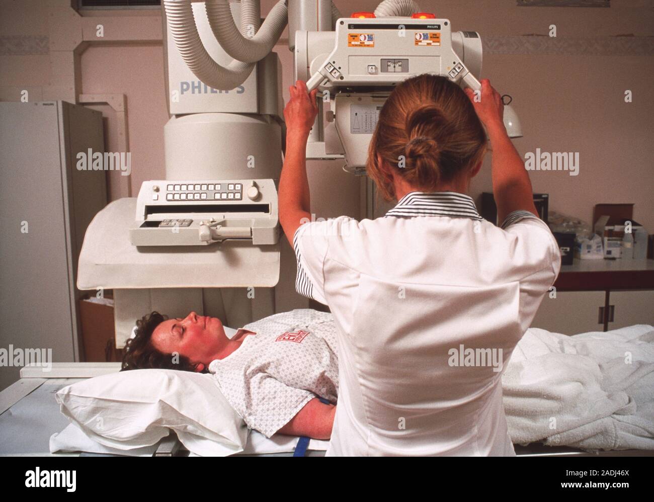 Urography. Radiologist adjusting an X-ray machine before taking a ...