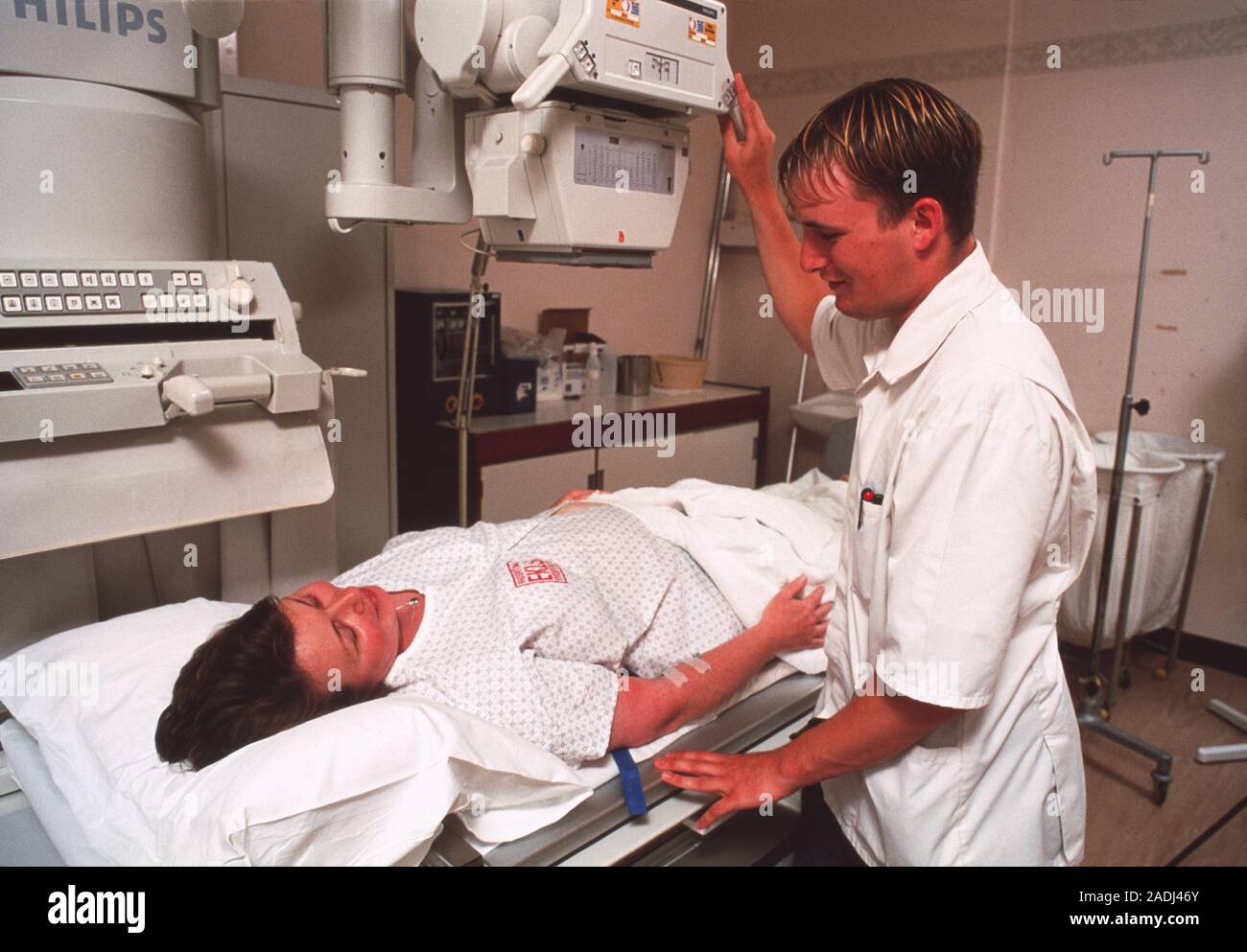 Urography. Radiologist adjusting an X-ray machine before taking a ...