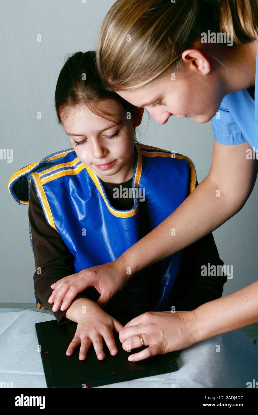 Hand X-ray. Radiographer positioning a girl's hand on a photographic ...