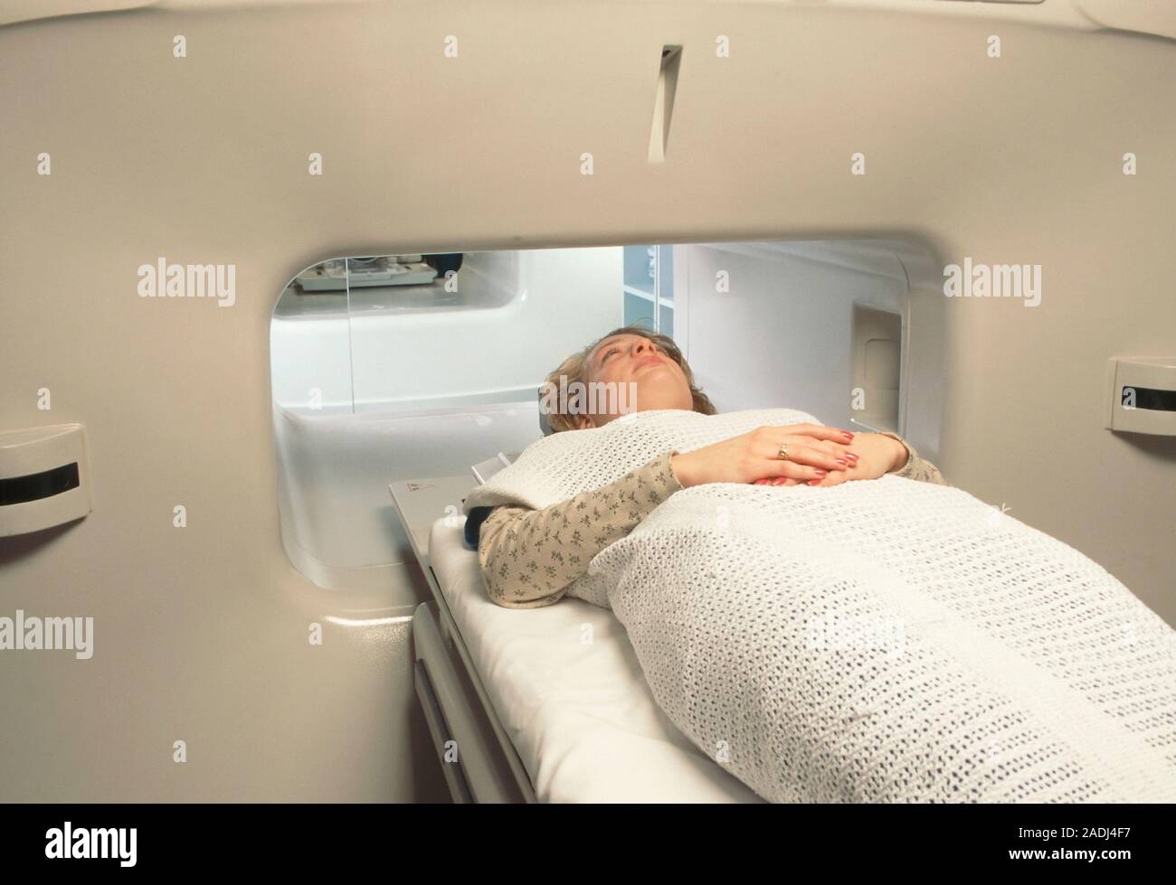MRI scanner. Lying on her back, a woman enters the extra-wide chamber ...