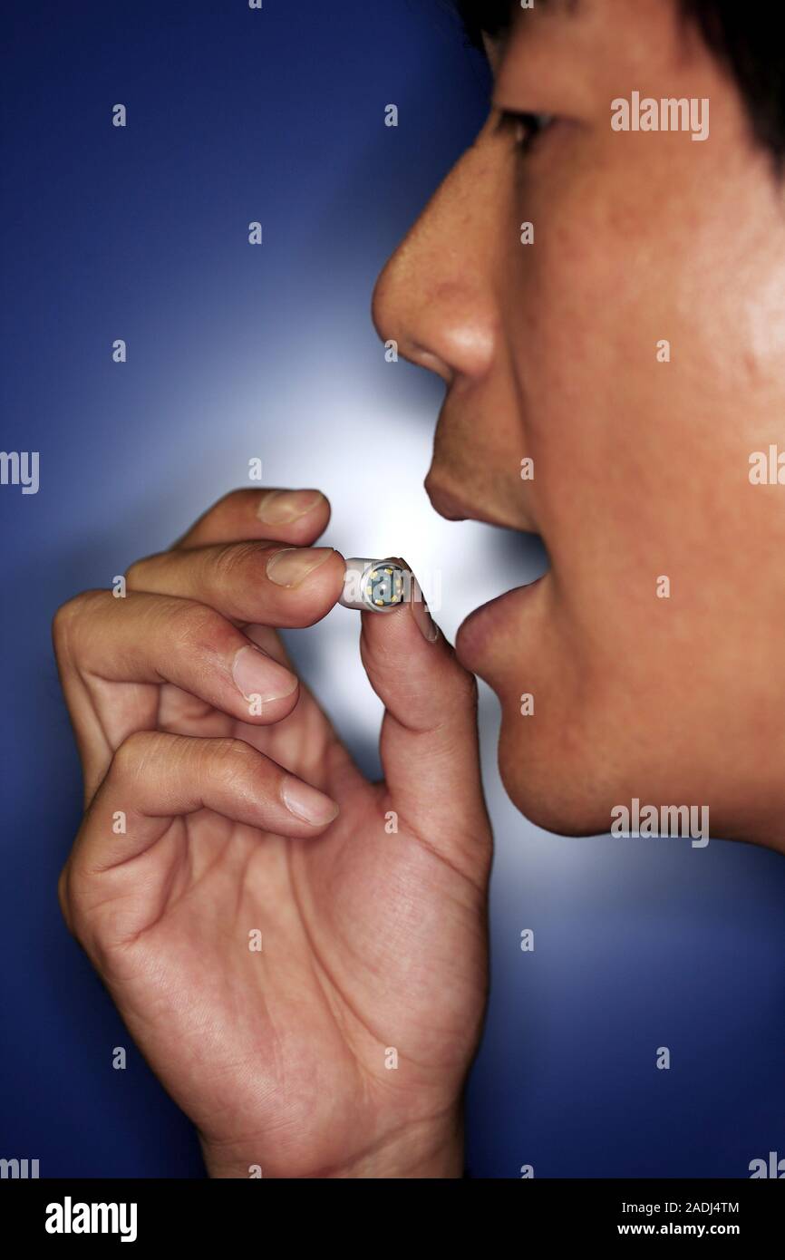 MODEL RELEASED. Capsule endoscope. Man about to swallow a capsule ...