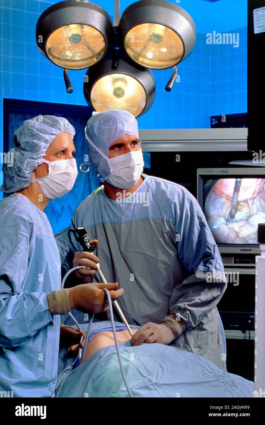 Surgeons performing a laparoscopic operation on a patient's abdomen. A ...