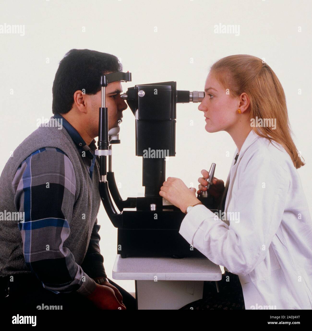 Optician examining a man's eyes using a non-contact ophthalmotonometer ...