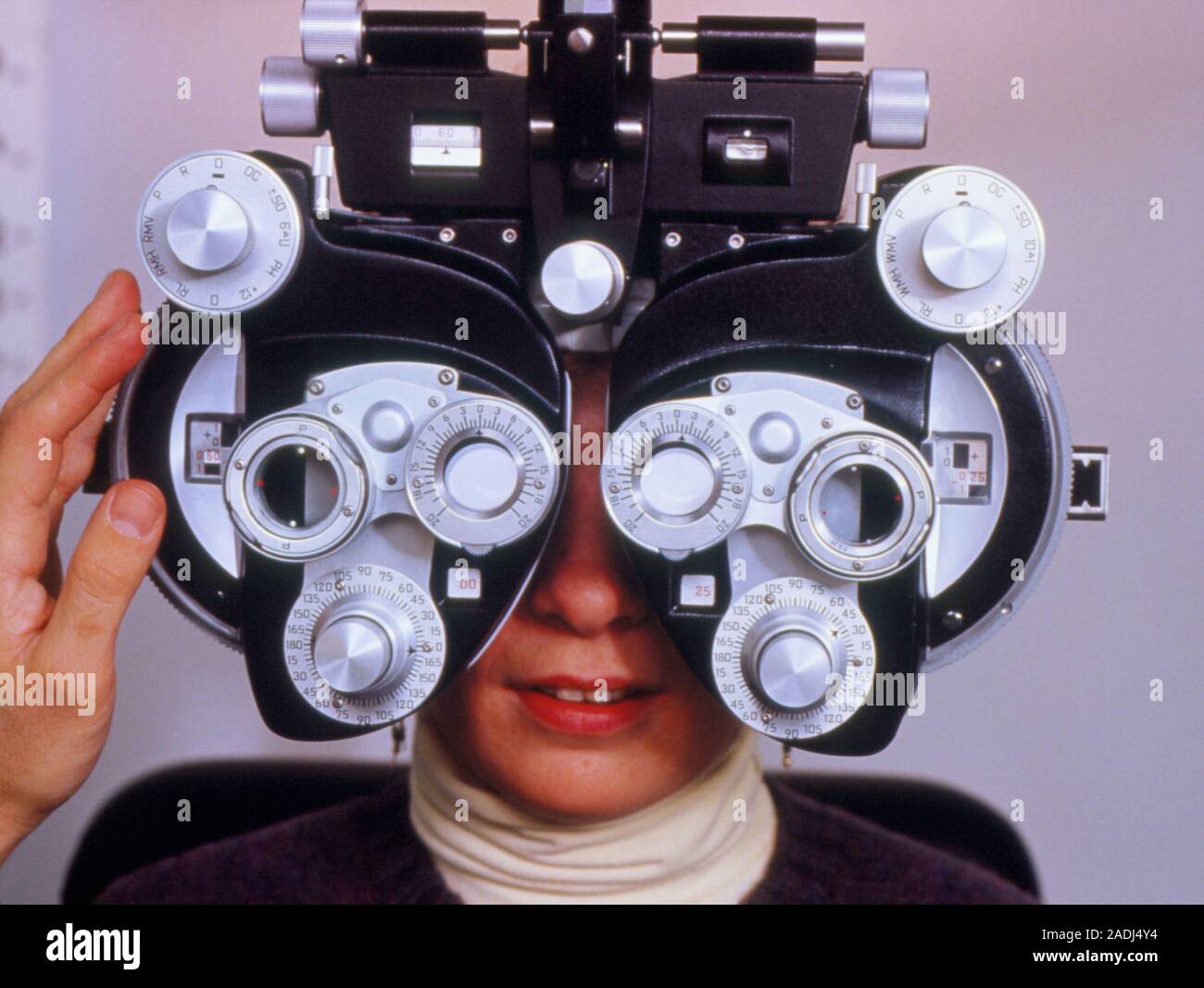 Eye examination. Young woman looks through a refractor during an eye ...
