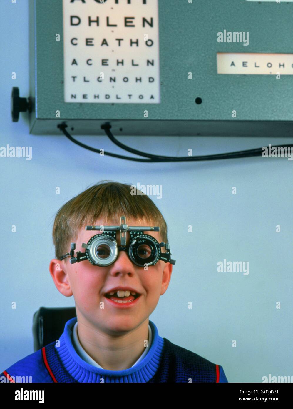 Eye test. Ophthalmology test frames fitted to a young boy for assessing ...