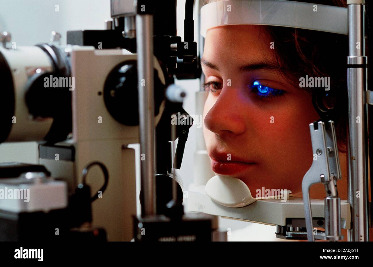 Eye examination. Girl having her eye examined by a fundus camera. This ...