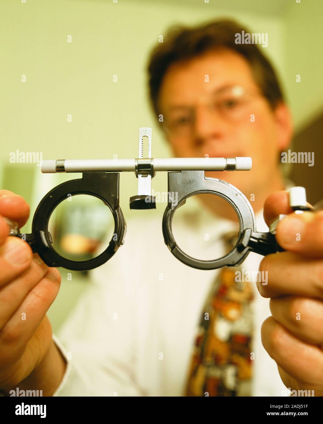 Optician holding eye test frames during an eye examination. Test frames ...