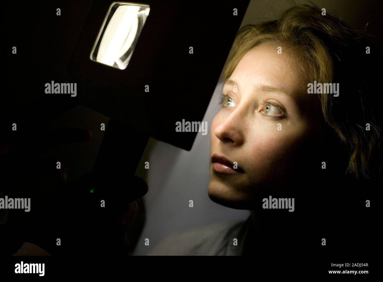 MODEL RELEASED. Eye examination. Burton lamp being used to check the ...