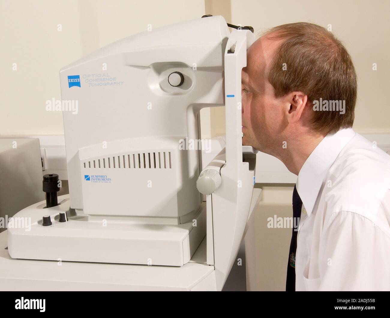 Eye examination. Patient having his eyes examined by a OCT (optical ...