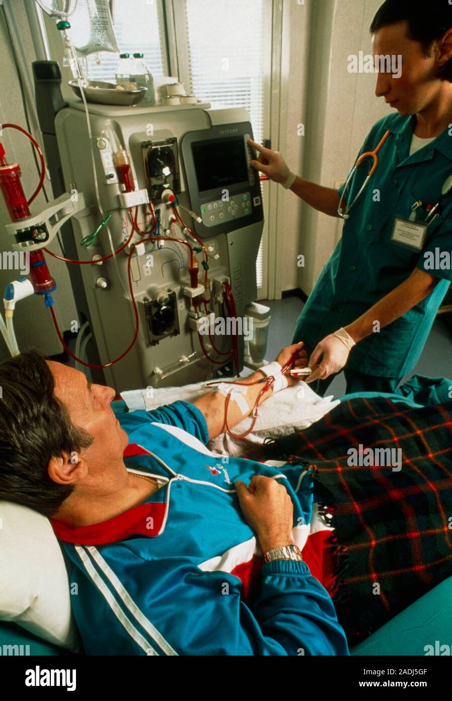 Renal dialysis. Male nurse assisting a male patient who is undergoing ...