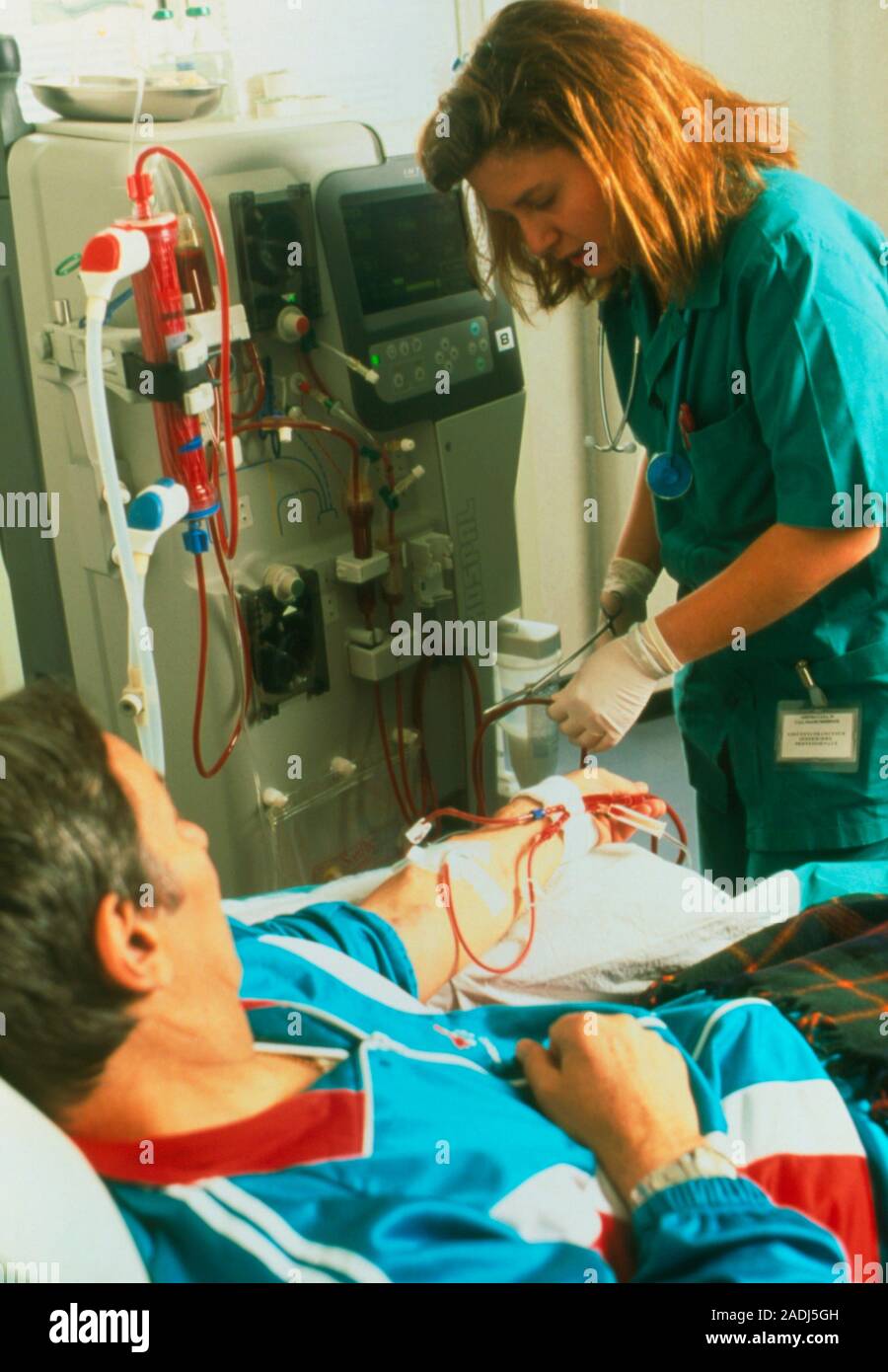 Renal dialysis. Female nurse assisting a male patient who is undergoing ...
