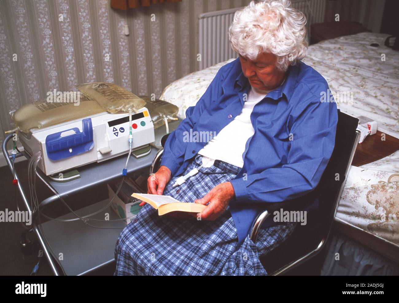 Kidney dialysis. 70-year-old woman reading a book at home during ...