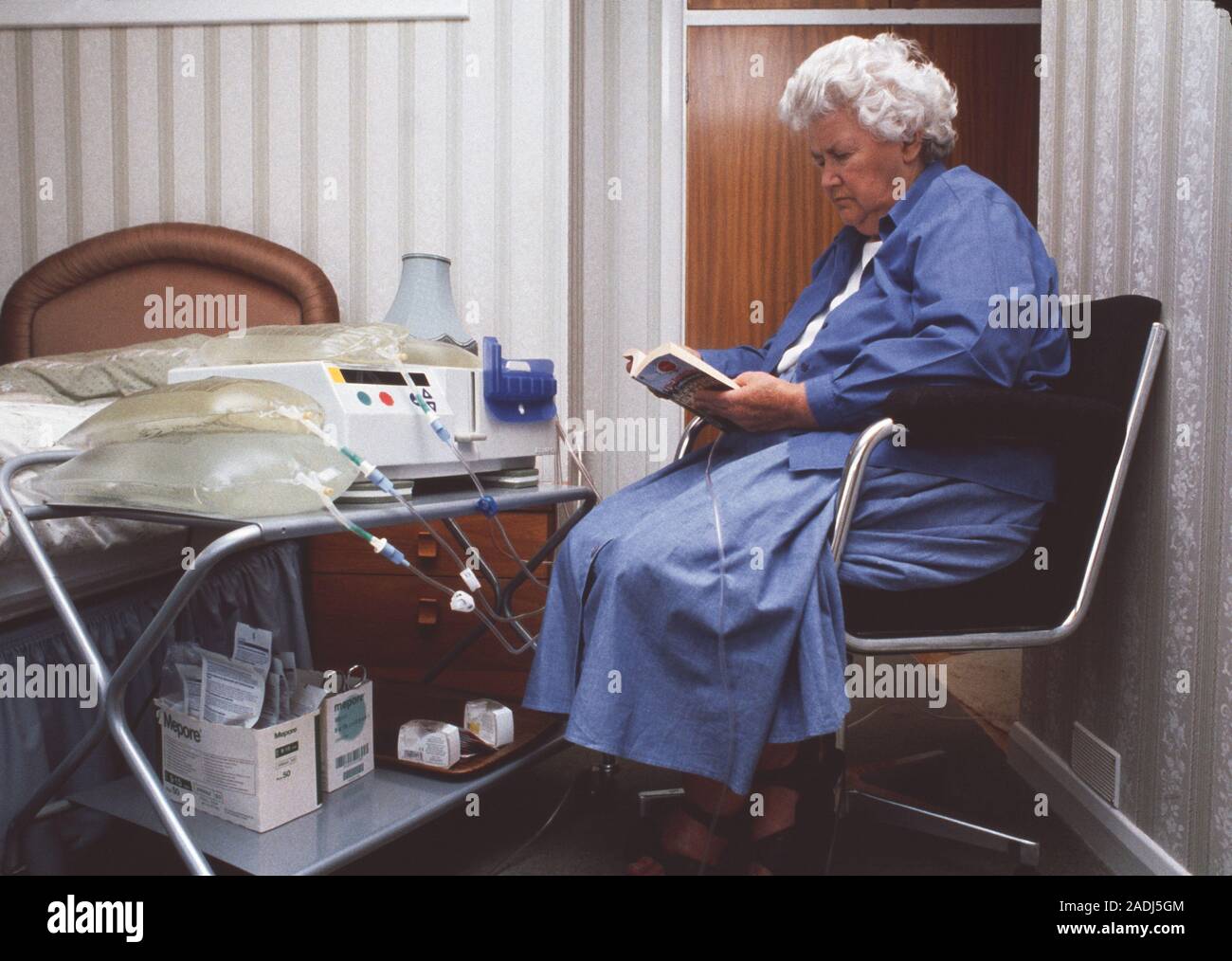Kidney dialysis. 70-year-old woman reading a book at home during ...