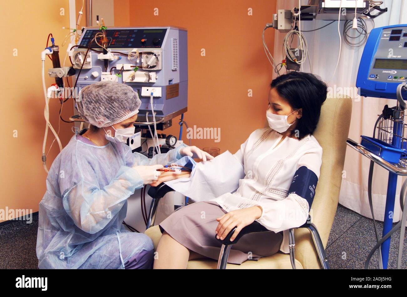 Kidney dialysis. Nurse inserting a needle into a patient's wrist before ...