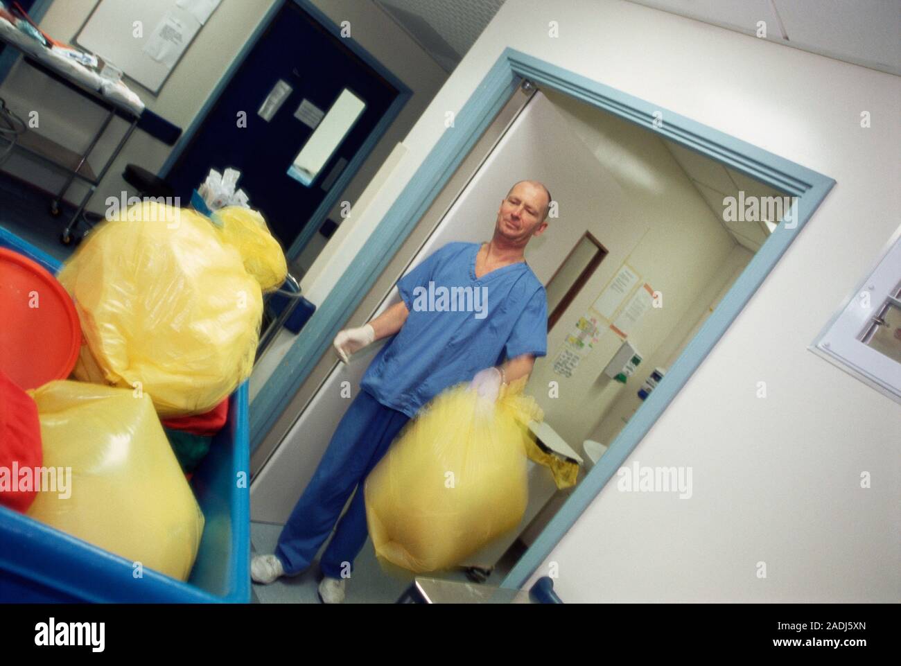 MODEL RELEASED. Hospital cleaner disposing of bags of medical waste ...