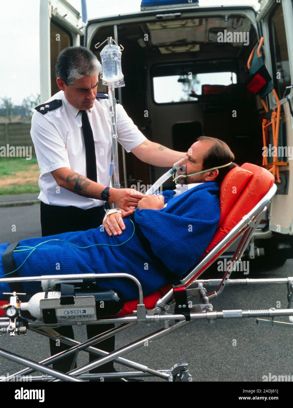 Ambulanceman adjusting a patient's oxygen mask before loading him into ...