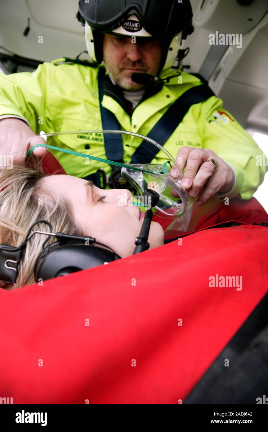 Air ambulance treatment. Paramedic placing an oxygen mask on a patient ...