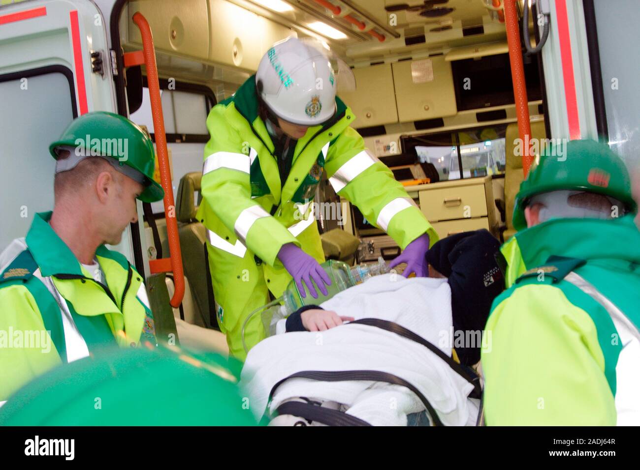 Emergency treatment. Paramedics loading a patient onto an ambulance ...