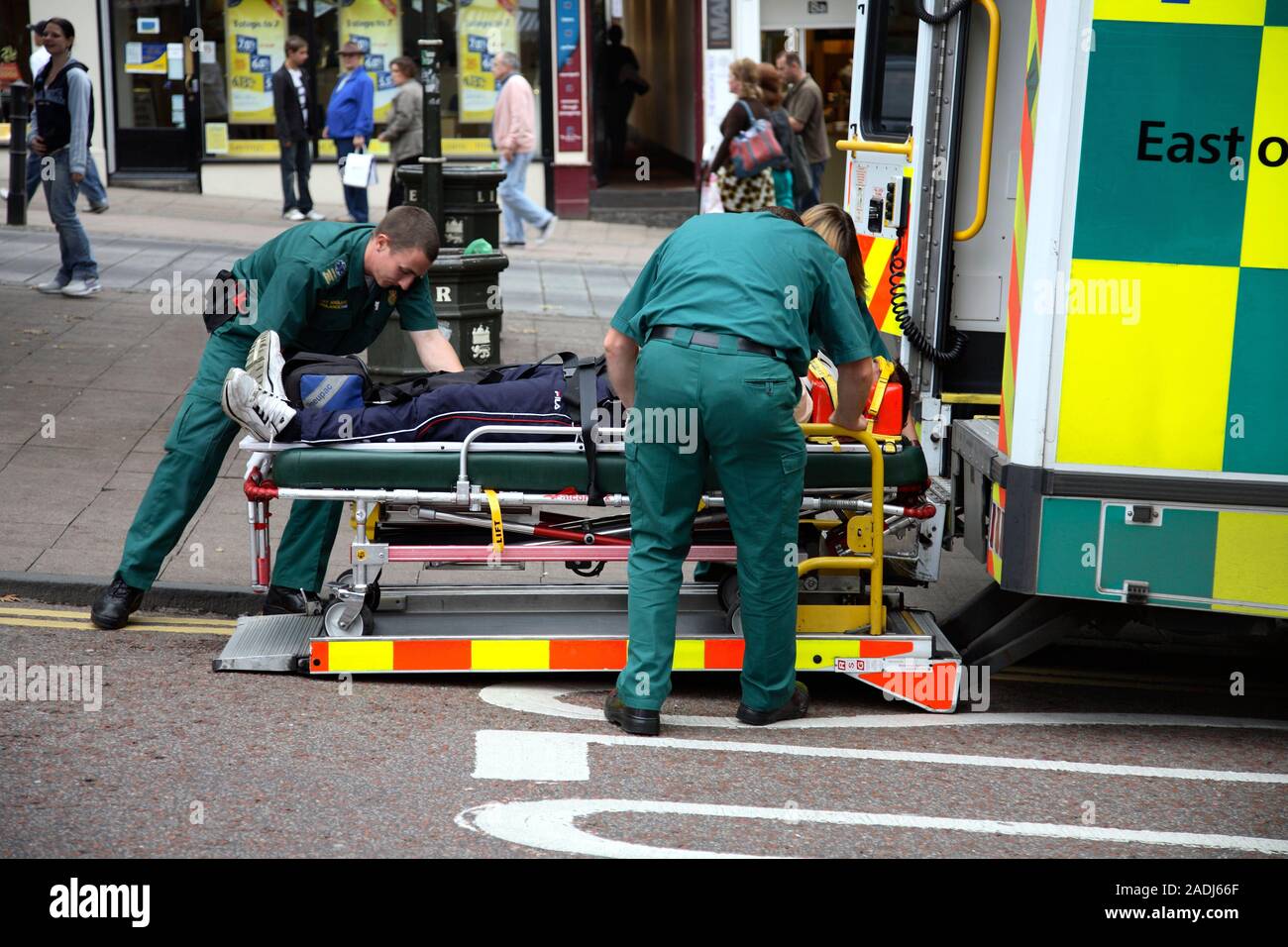 Emergency treatment. Paramedics loading a patient into an ambulance ...