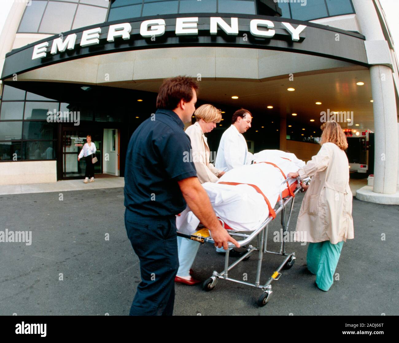 Emergency treatment. Male patient on a stretcher is wheeled into the ...